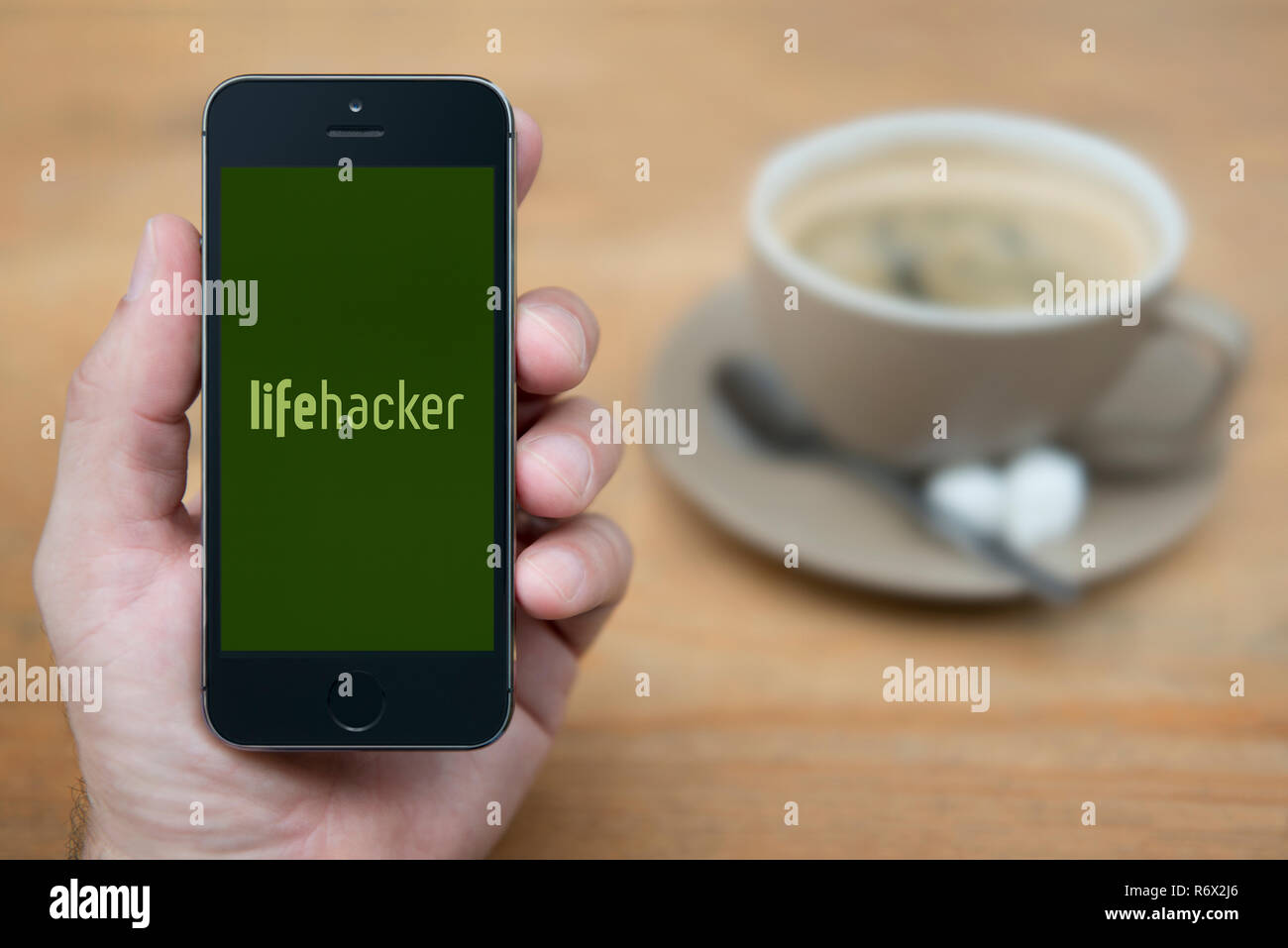 A man looks at his iPhone which displays the LifeHacker logo (Editorial use only Stock Photo - Alamy