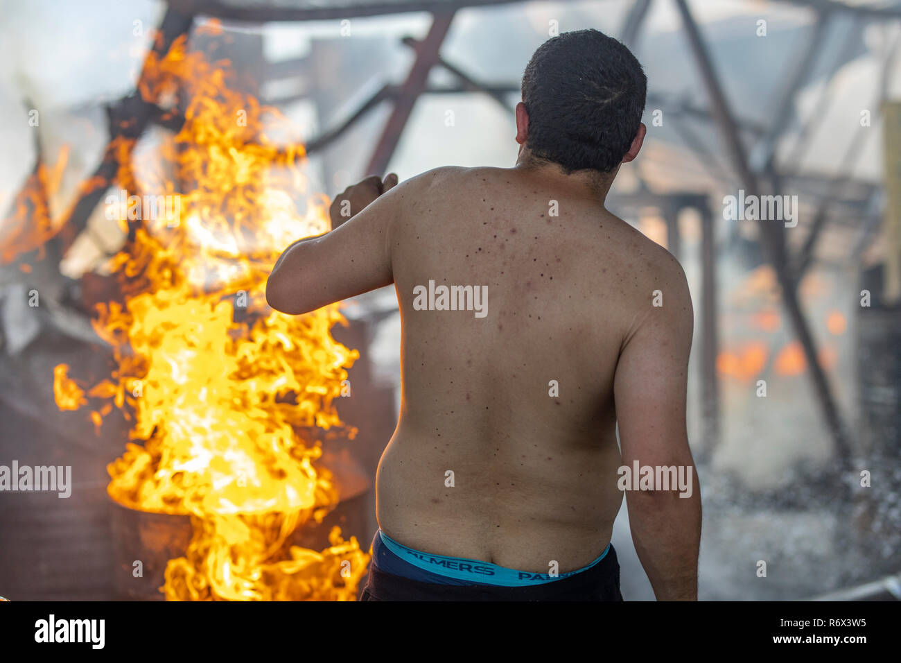 Man in front of a fire and flames at a workshop in the industrial area ...