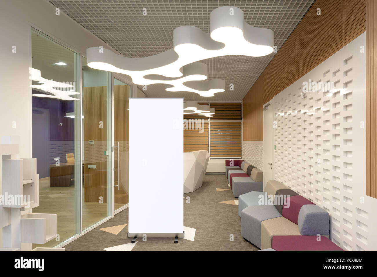 Blank roll up banner stand in office interior with waiting area. with ...
