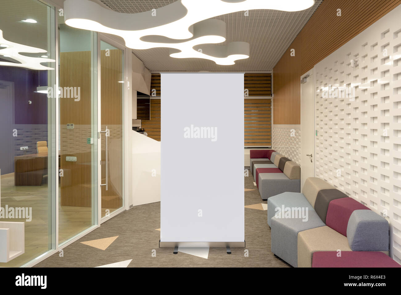 Blank roll up banner stand in office interior with waiting area. with ...
