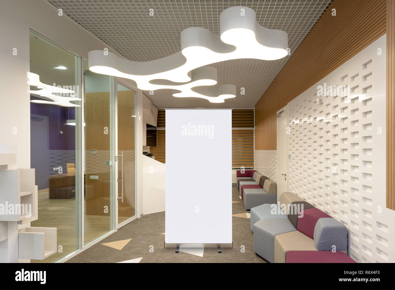 Blank roll up banner stand in office interior with waiting area. with ...