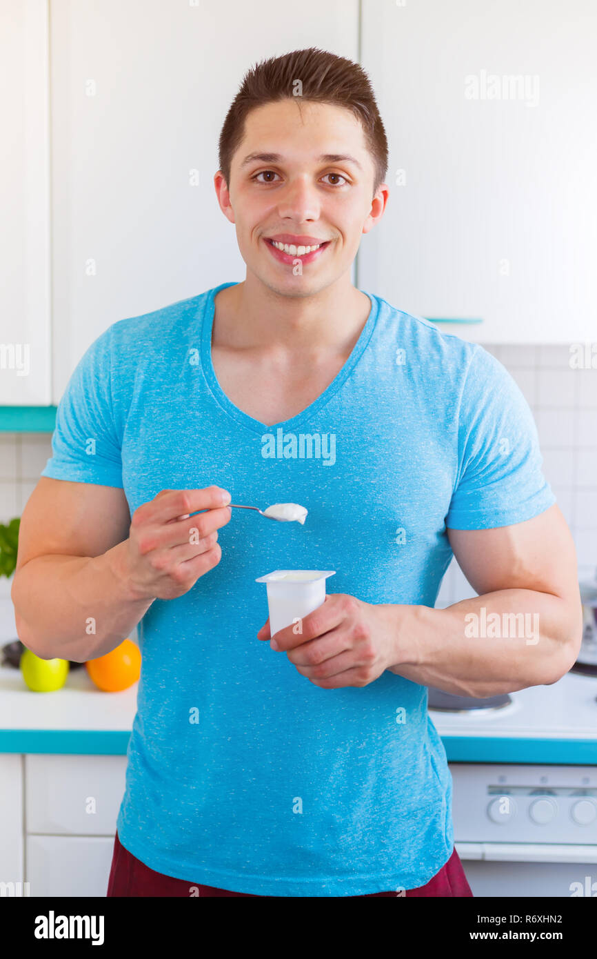 healthy eating young man eating yogurt in the kitchen portrait of ...