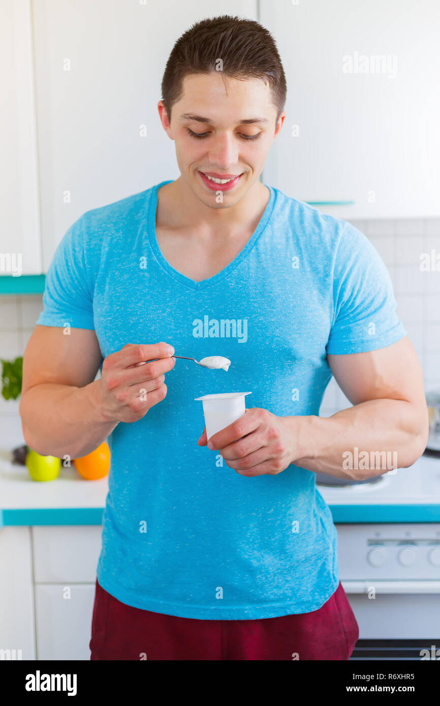 young man eats eating yogurt in the kitchen healthy eating portrait ...