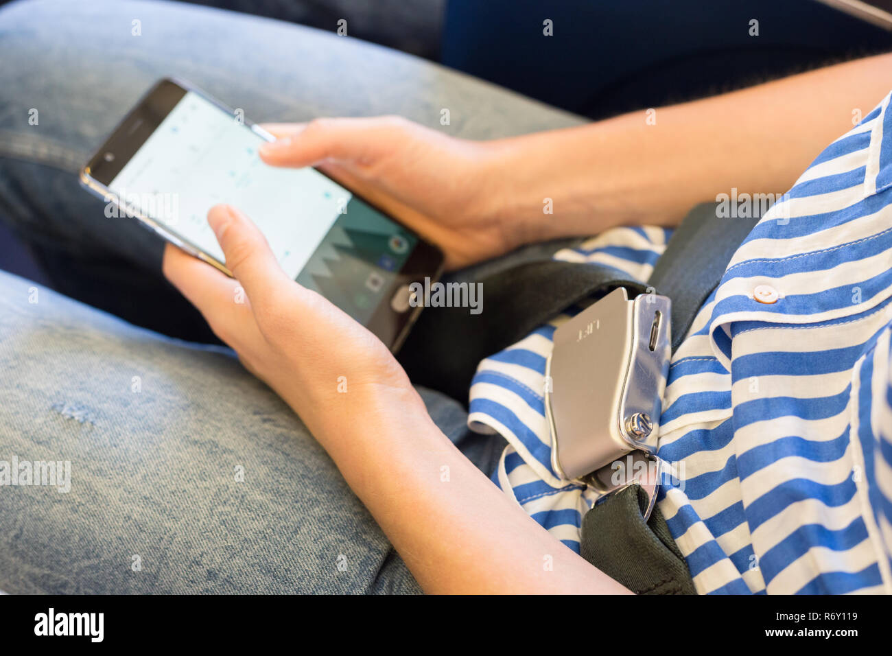 Female passenger with seat belt fastened switching mobile phone to ...