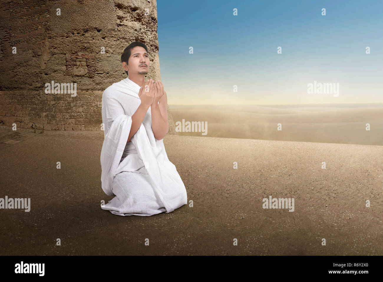 Handsome asian pilgrim kneeling and praying Stock Photo - Alamy