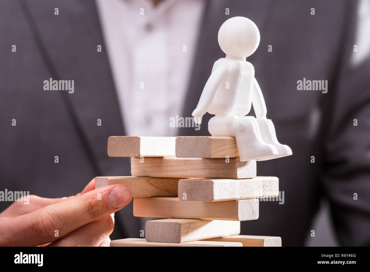 Human Figure Sitting On Top Of Stacked Wooden Blocks Stock Photo - Alamy