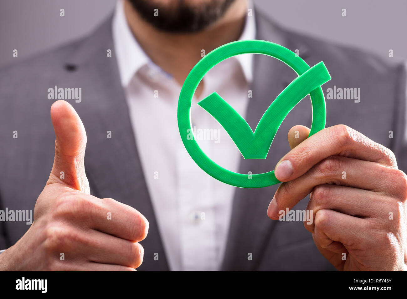 Businessperson Holding Check Mark Icon Stock Photo - Alamy