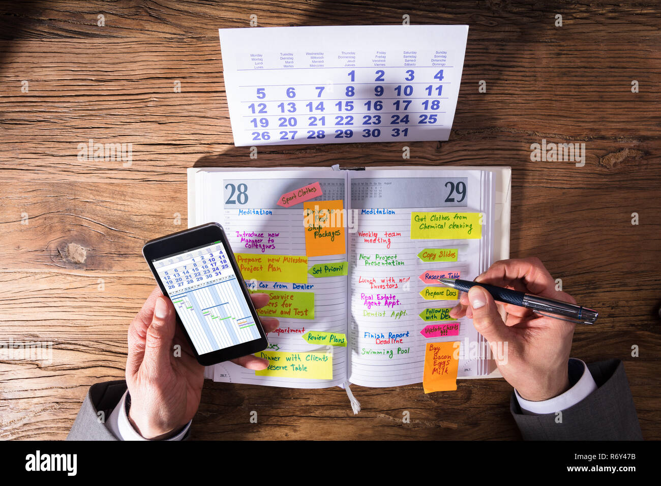 Businessperson With Mobile Phone Writing Schedule In Diary Stock Photo ...