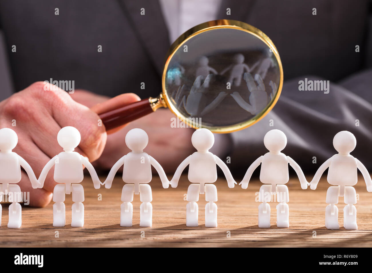 Hand Holding Magnifying Glass Over Red Human Figures Stock Photo - Alamy