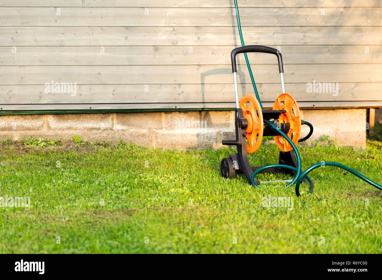 Garden hose on the house wall background. gardening and watering ...