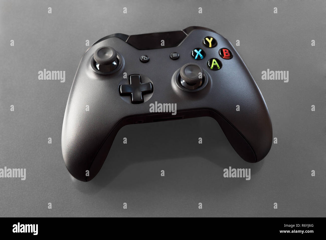 Top view of a logo free, black videogame controller on grey background ...