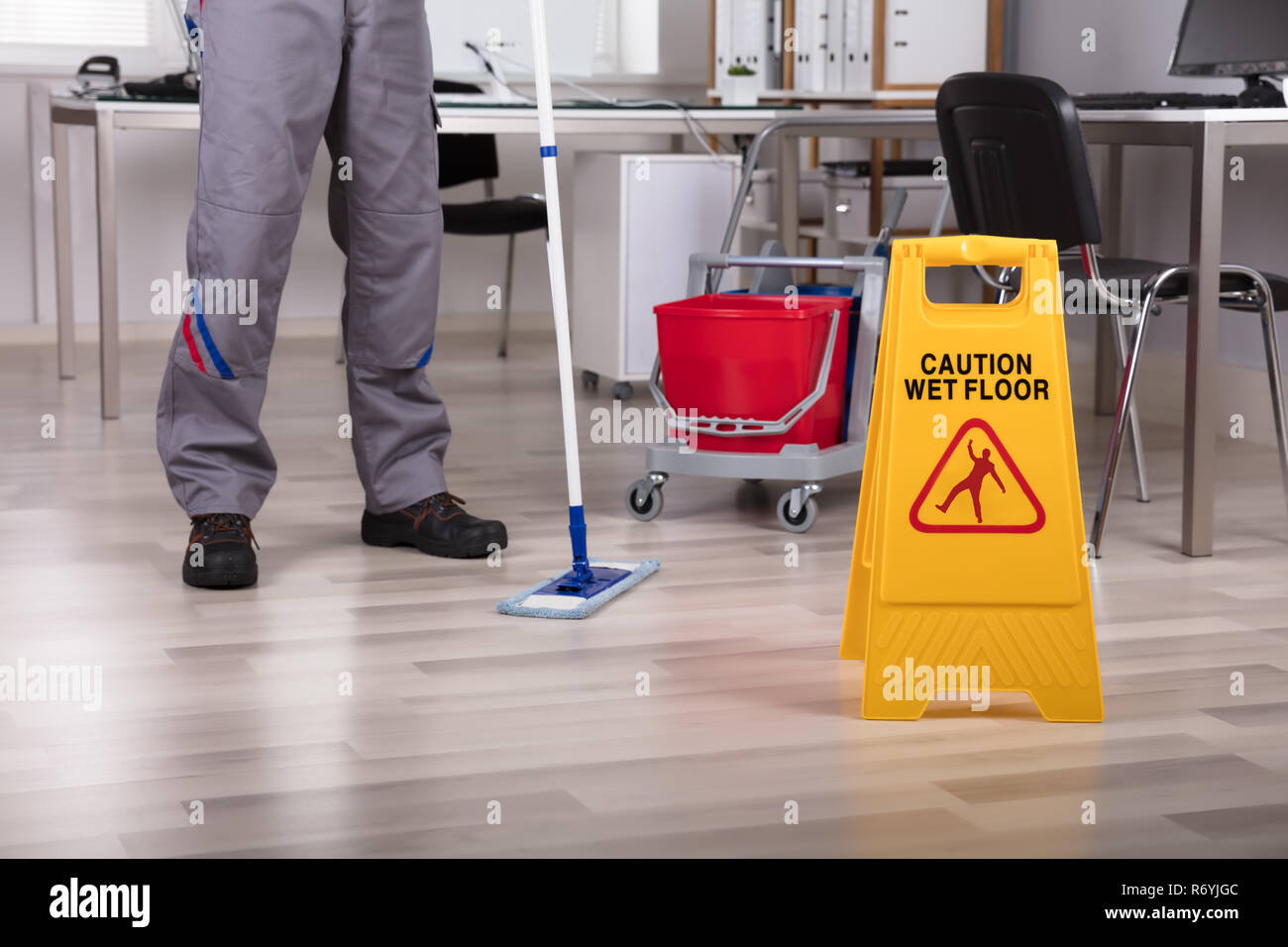 Cleaner Standing With Mop And Caution Wet Floor Sign Stock Photo - Alamy
