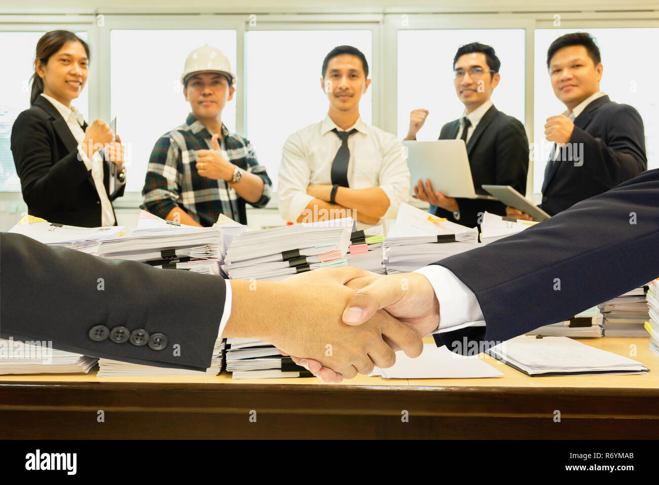 Business handshake successful with pile of paperwork and group of ...