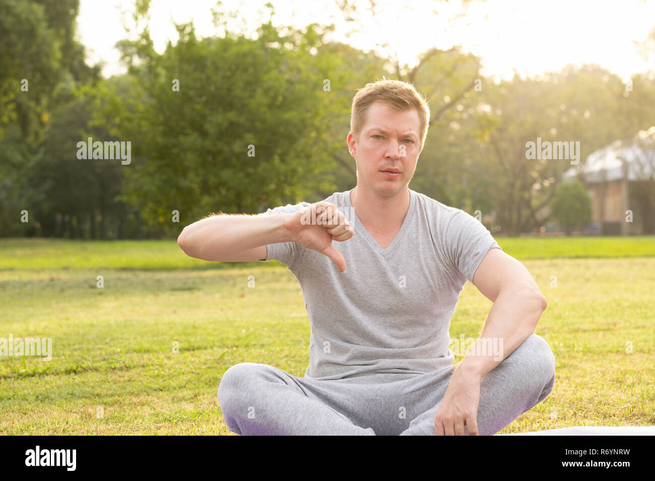 Young man looking frustrated and giving thumbs down at the park Stock ...
