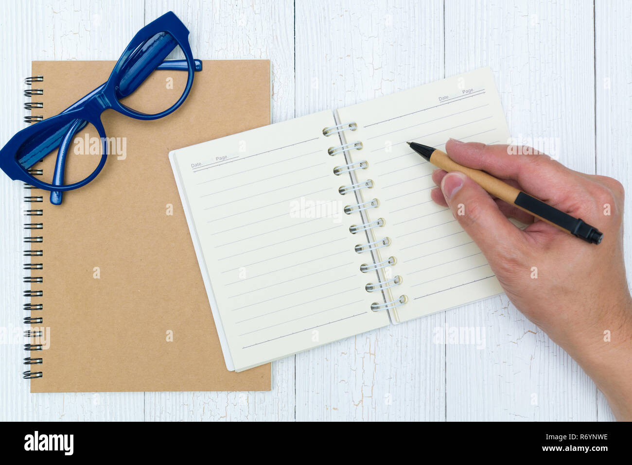 Man hand writing on blank page of notebook paper with pen on the wood ...