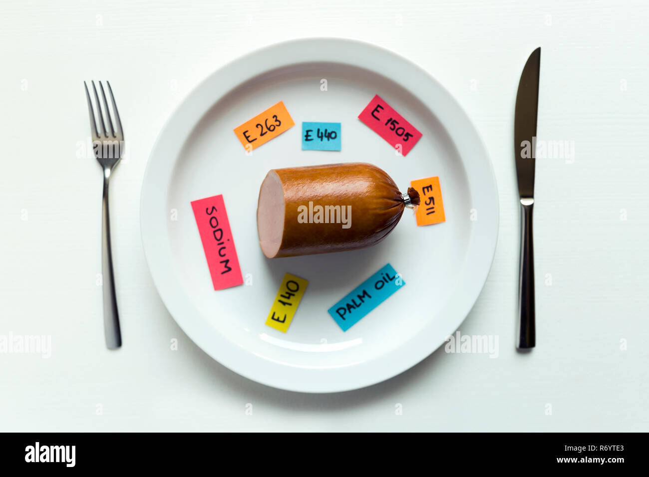 Colorful paper notes naming food additives and sausage on plate with ...