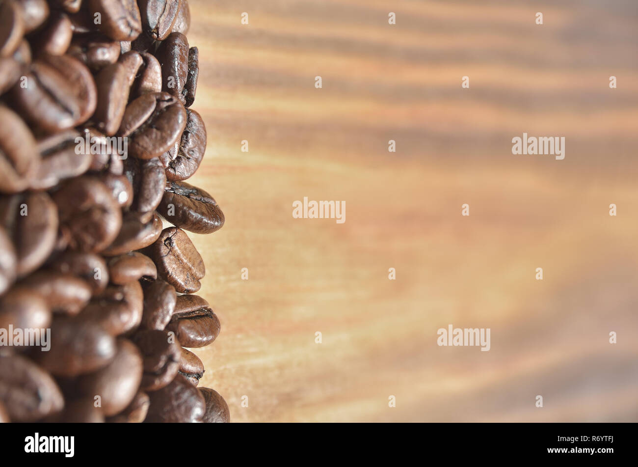 Beautiful fried coffee beans on a light wooden background, on the left ...