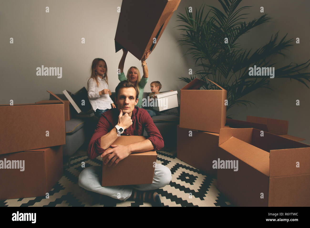 Picture of man sitting on floor among cardboard boxes and funny woman ...