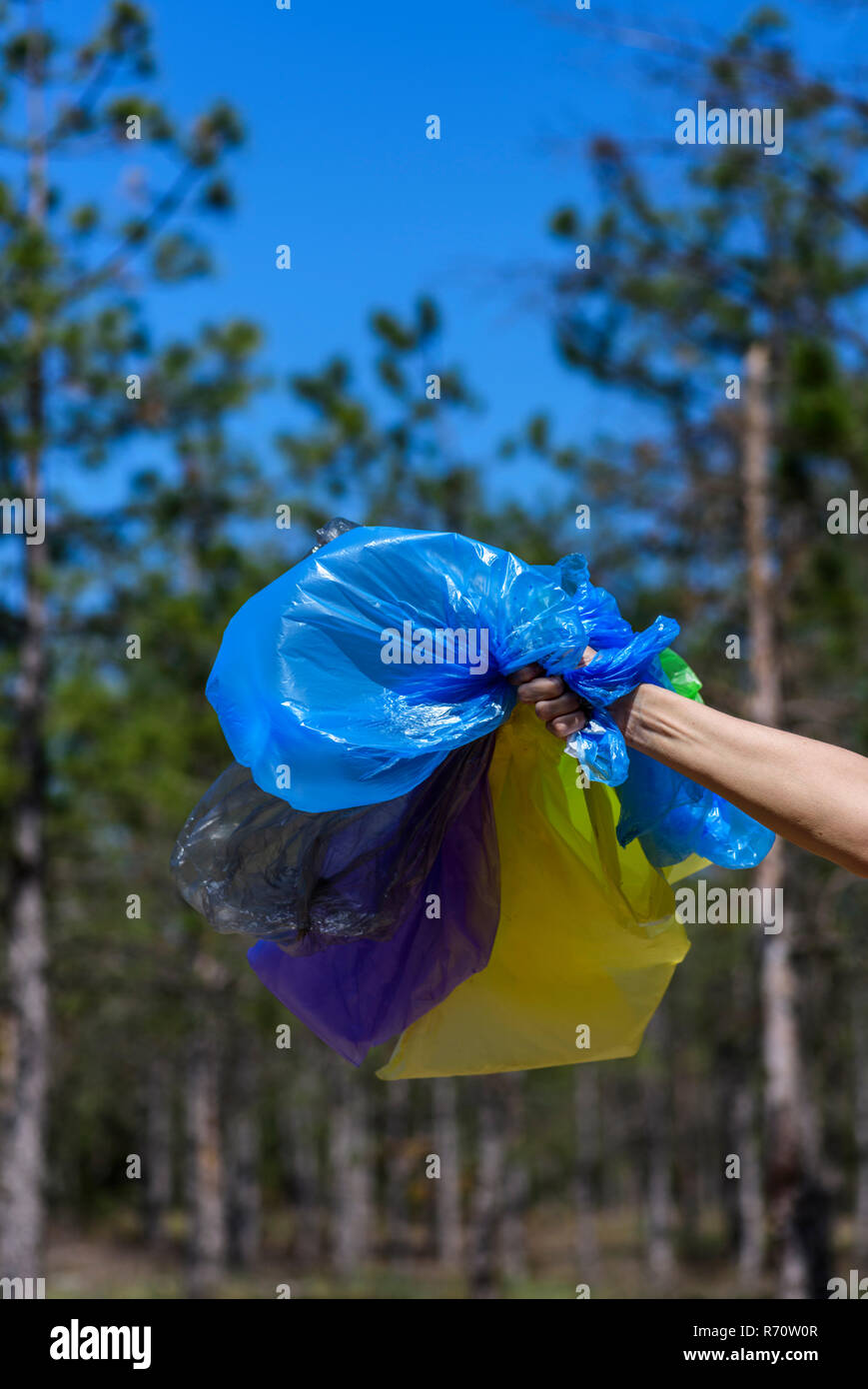human hand holds many multicolored empty transparent bags for garbage ...