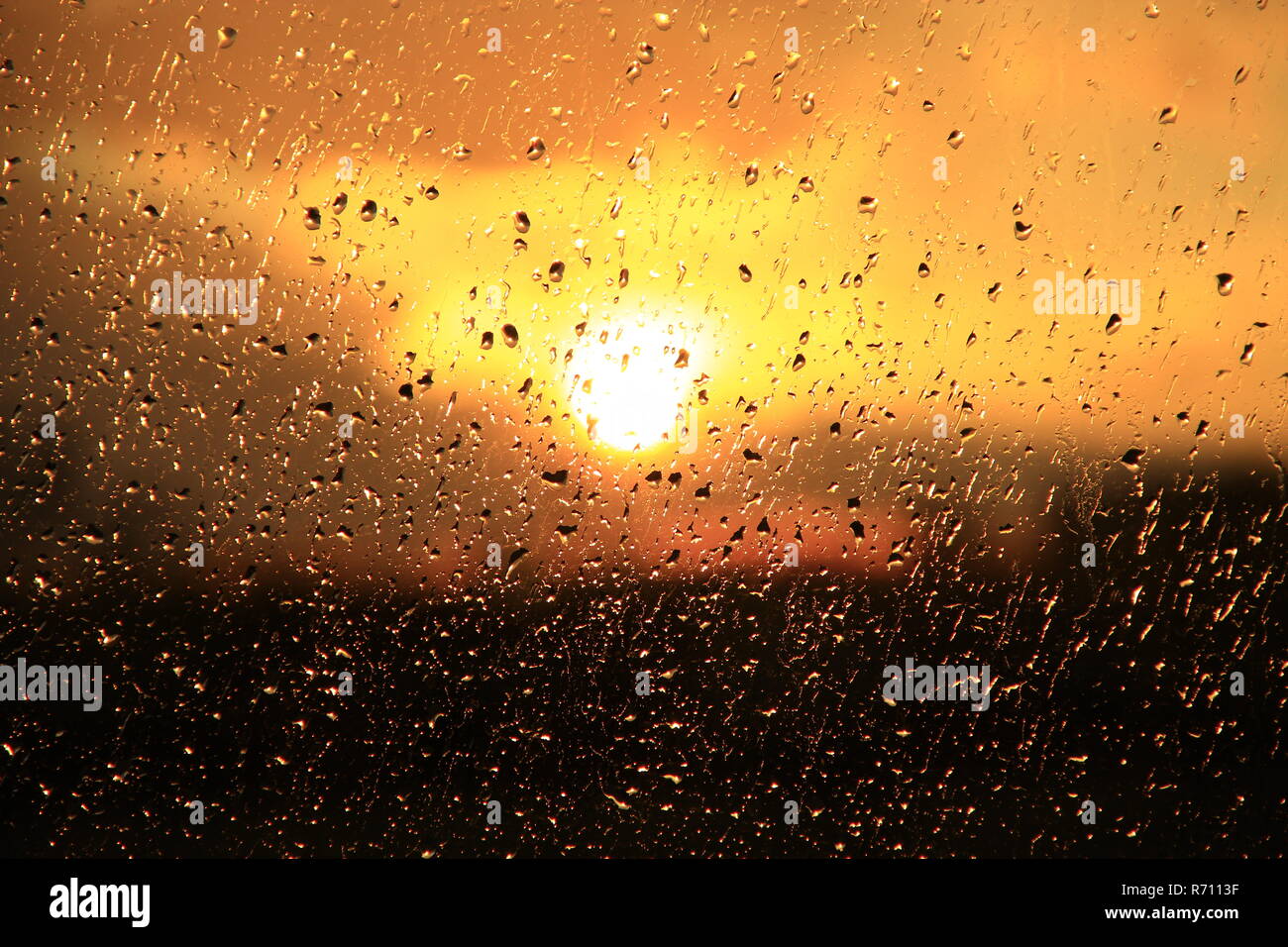 Rain outside window on sunset background. Water drops on glass during ...