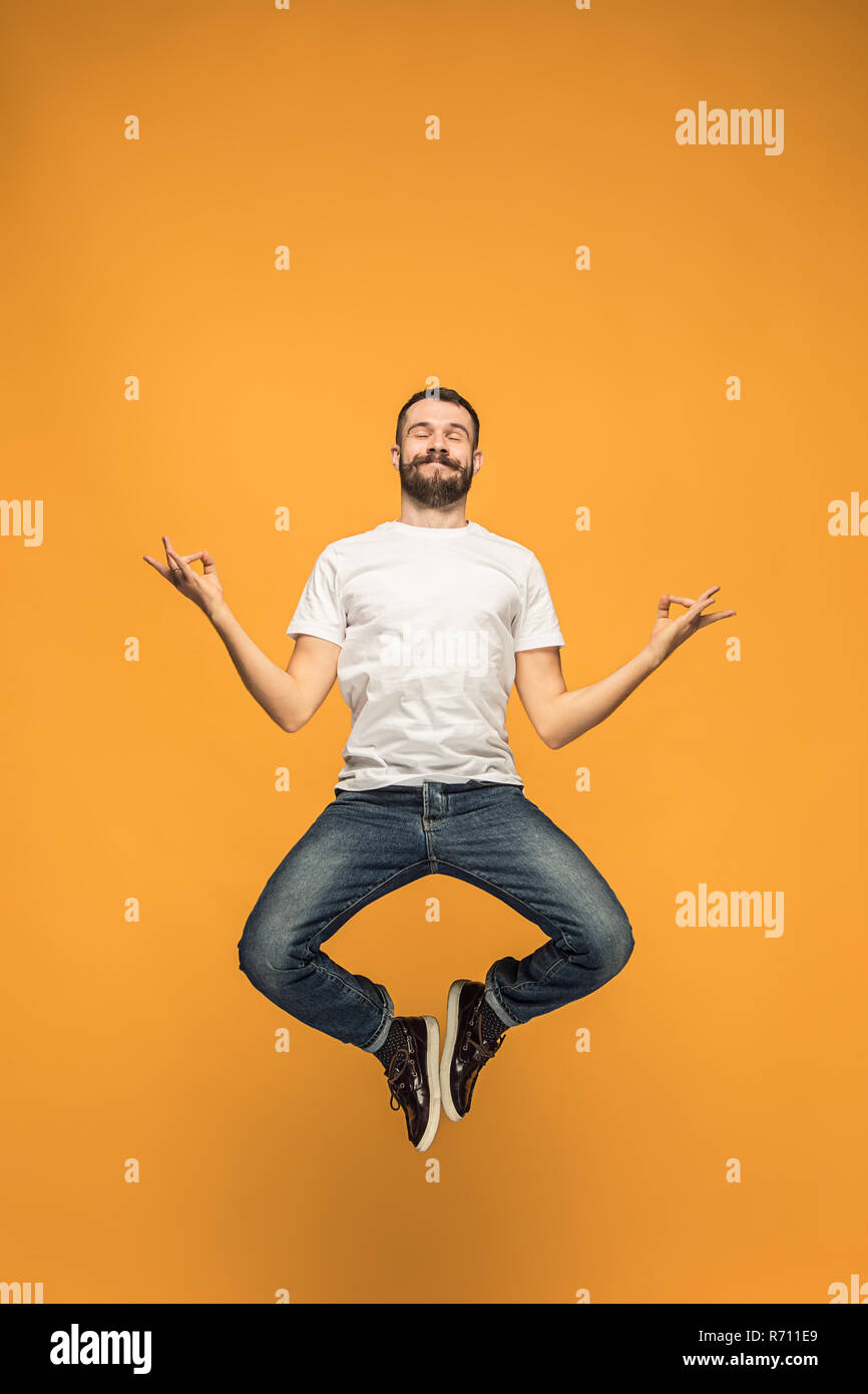 Freedom in moving. handsome young man jumping against orange background ...