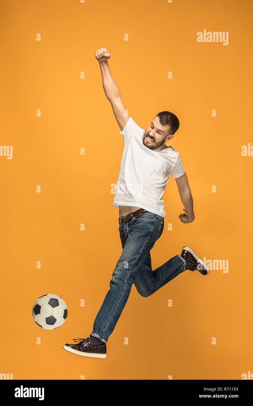 The young man as soccer football player kicking the ball at studio ...