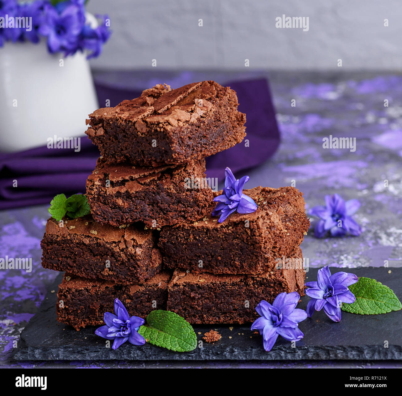 chocolate pieces of brownie pie are stacked on a black graphite plate ...