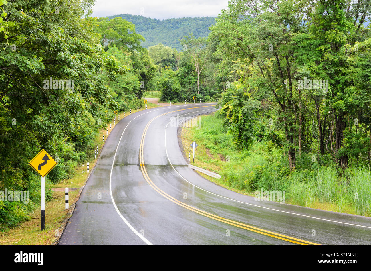 Wet mountain asphalt road after rain with traffic sign of sharp reverse ...