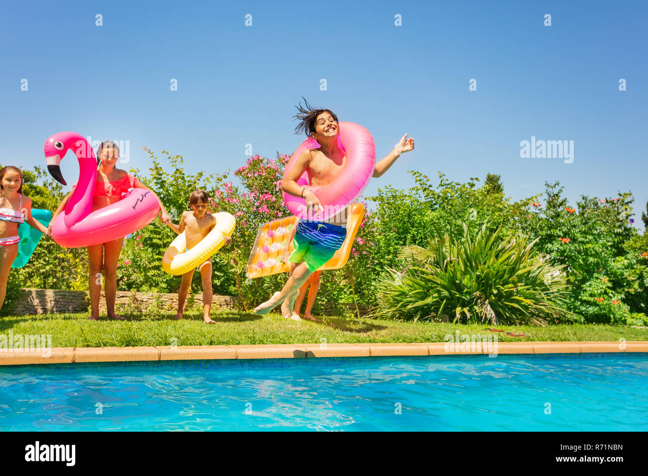 Boy in swim ring playing pool games with friends Stock Photo - Alamy