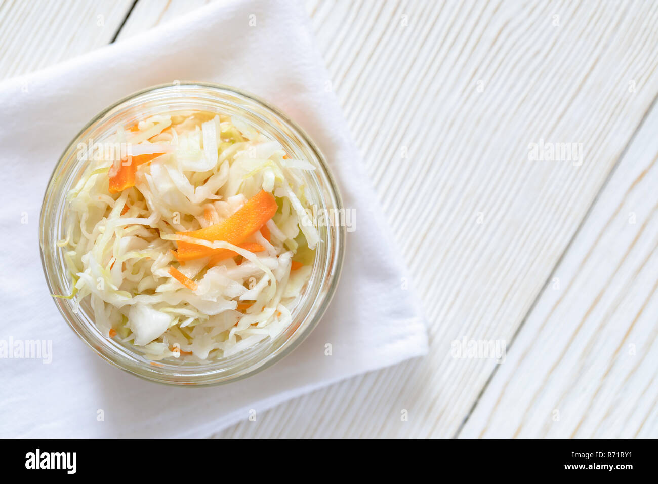 Top view glass jar with sauerkraut on white towel on white diagonal ...
