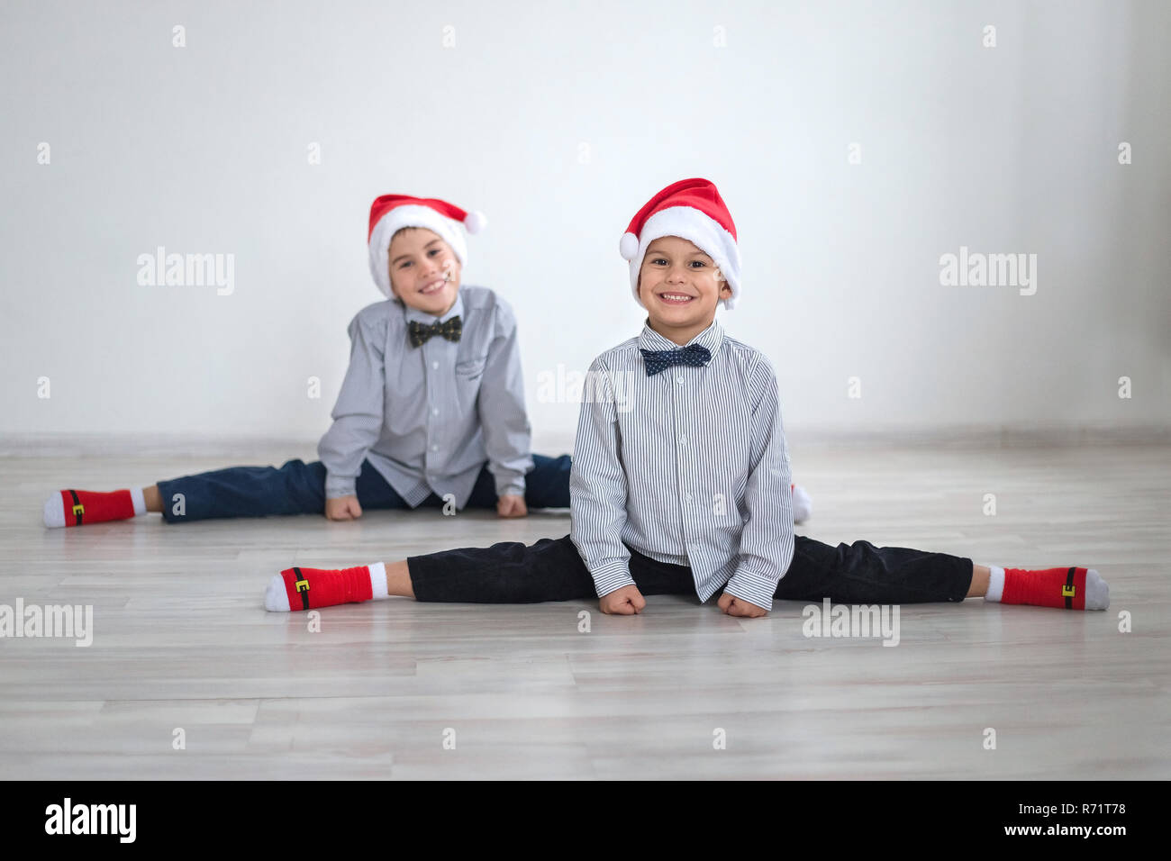 Two boys brother sitting on the splits in Santa hat Stock Photo - Alamy