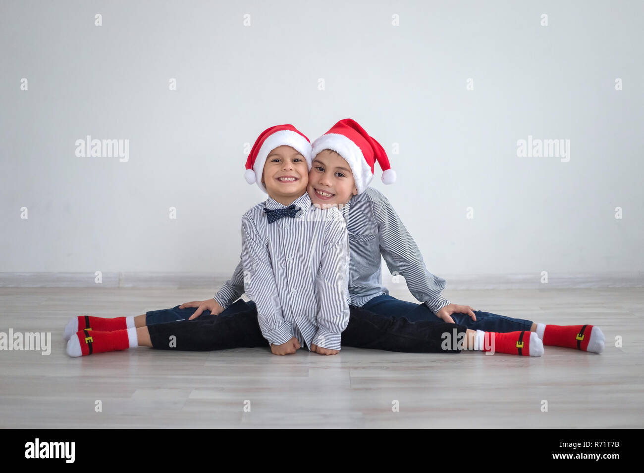 Two boys brother sitting on the splits in Santa hat Stock Photo - Alamy