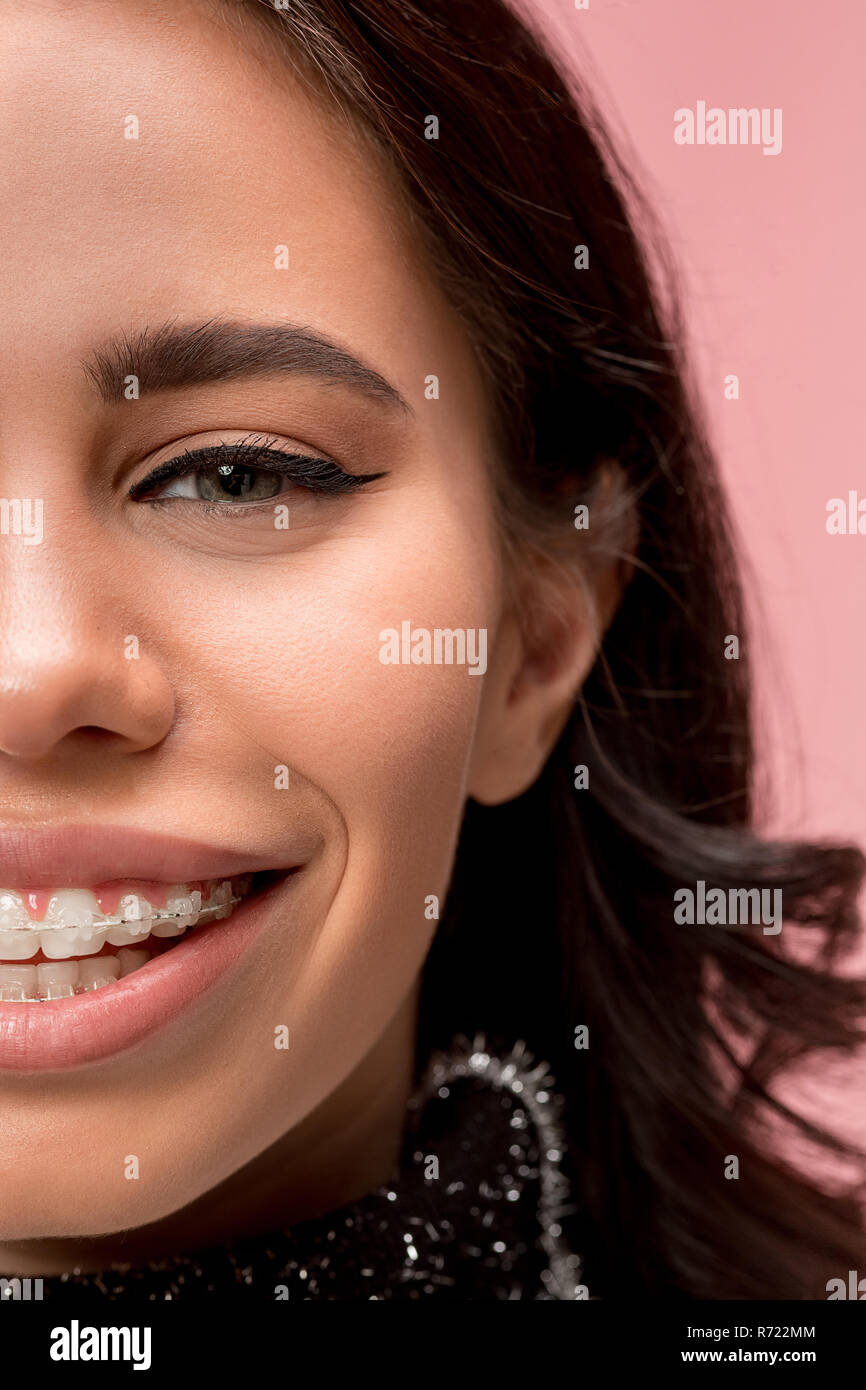Beautiful young woman with teeth braces on pink. half face of pretty ...