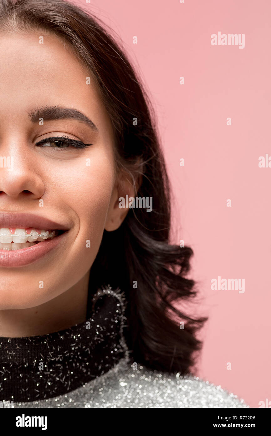 Beautiful young woman with teeth braces on pink. half face of pretty ...