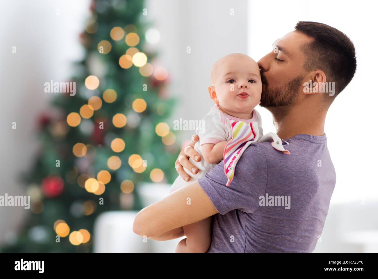father kissing baby daughter over christmas tree Stock Photo - Alamy