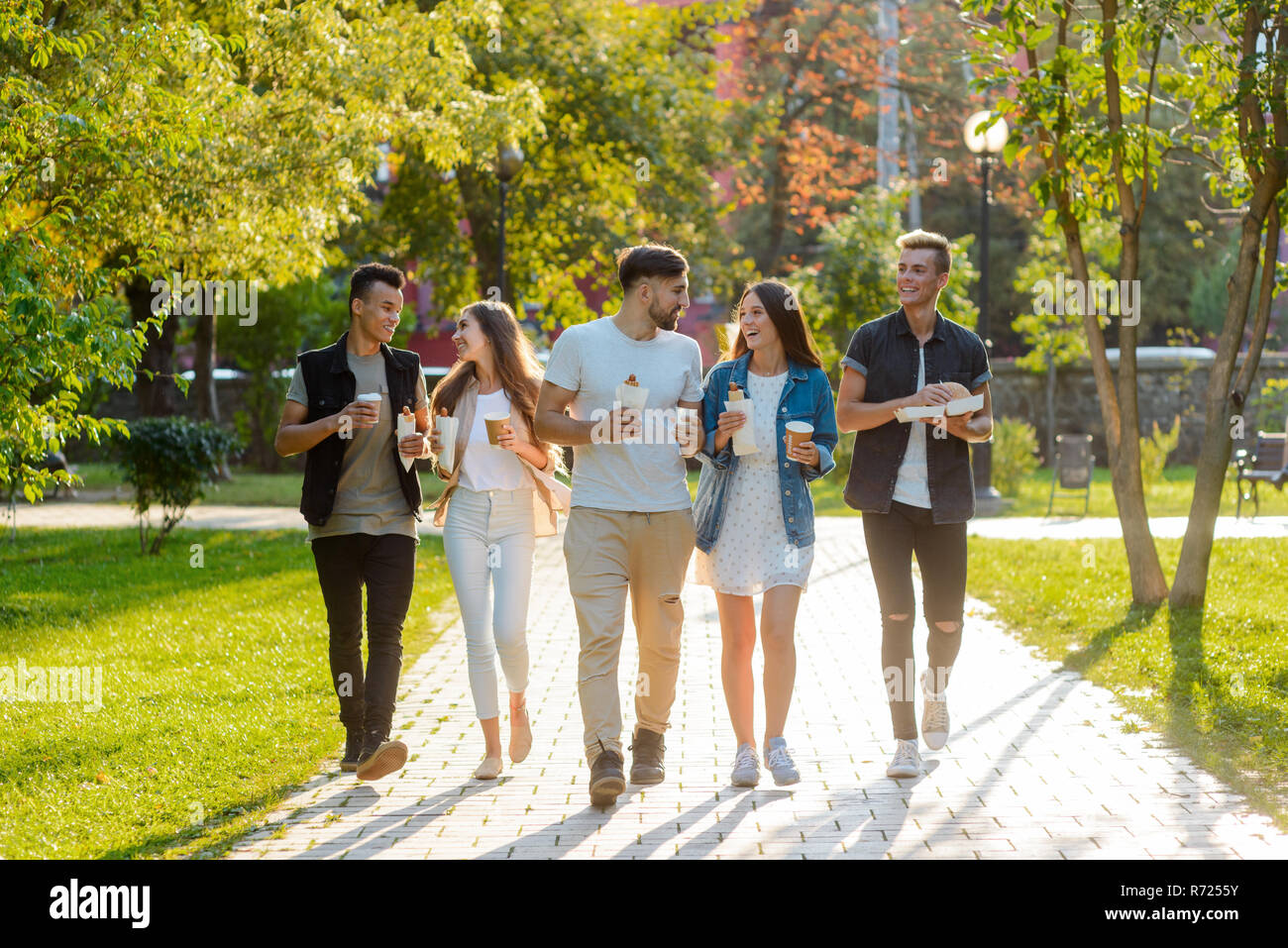 Friends walking and eating Stock Photo - Alamy