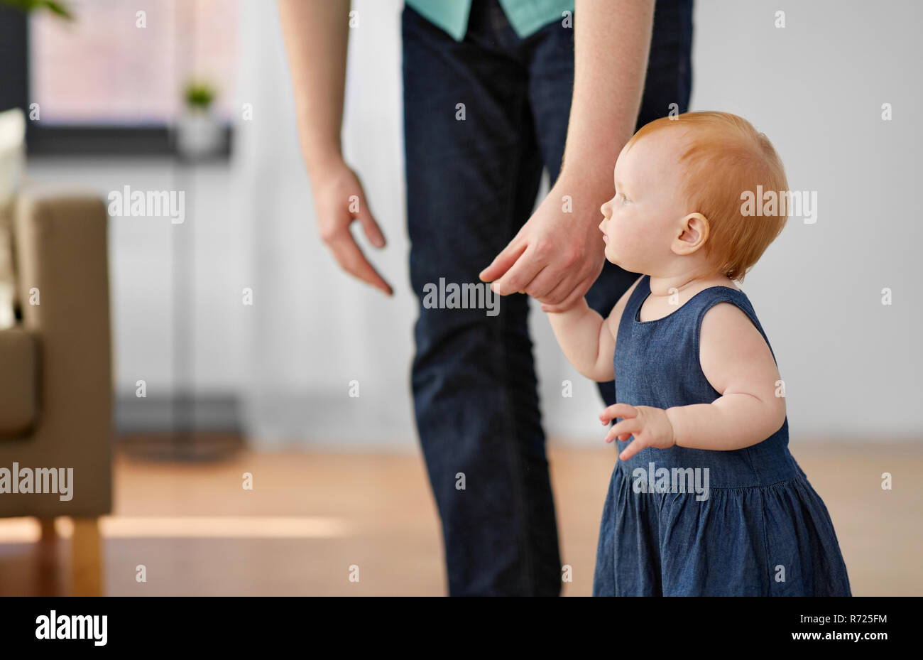 baby girl walking with father help at home Stock Photo - Alamy