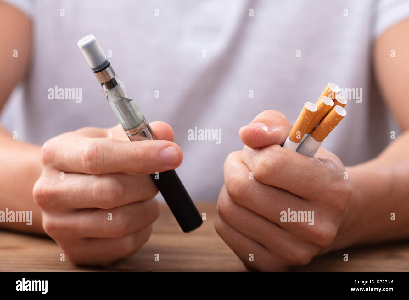 Man Holding Vape And Tobacco Cigarette Over Desk Stock Photo - Alamy