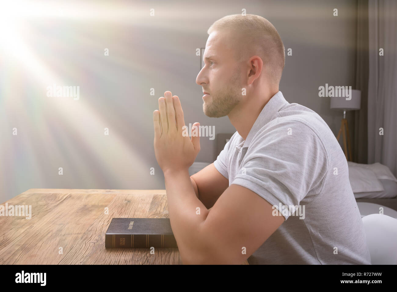 Side View Of A Young Man Praying With Bible Over Wooden Desk At Home ...