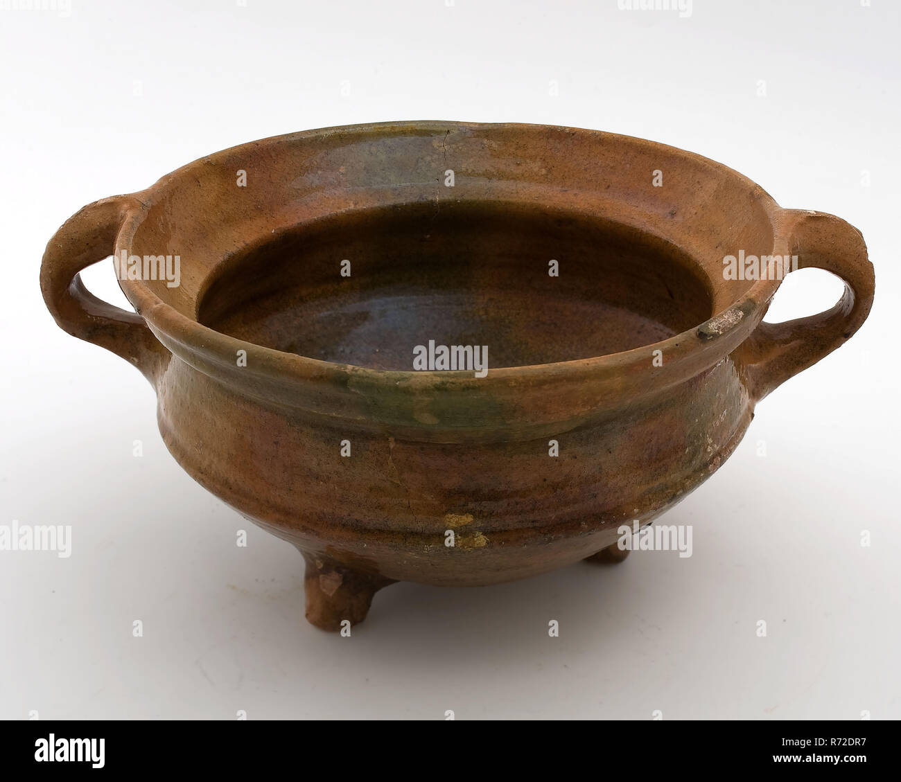 Earthenware cooking pot, glazed with two vertical bands, on three legs ...