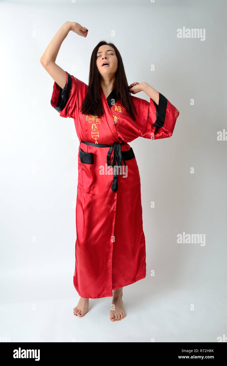 Young female wearing dressing-gown with white background. Awaking in ...