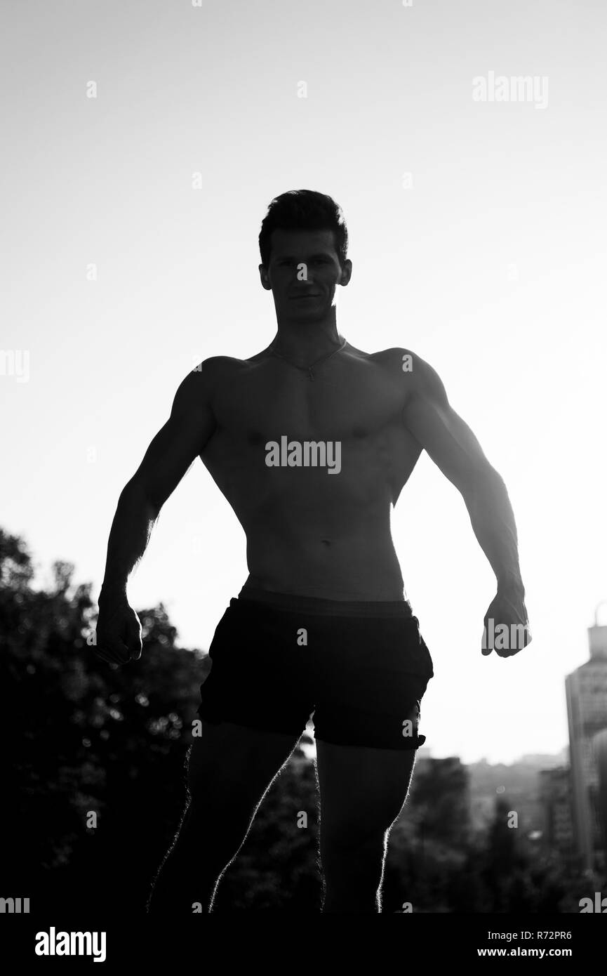 Bodybuilder showing muscular body, muscles, biceps, triceps on sunset ...