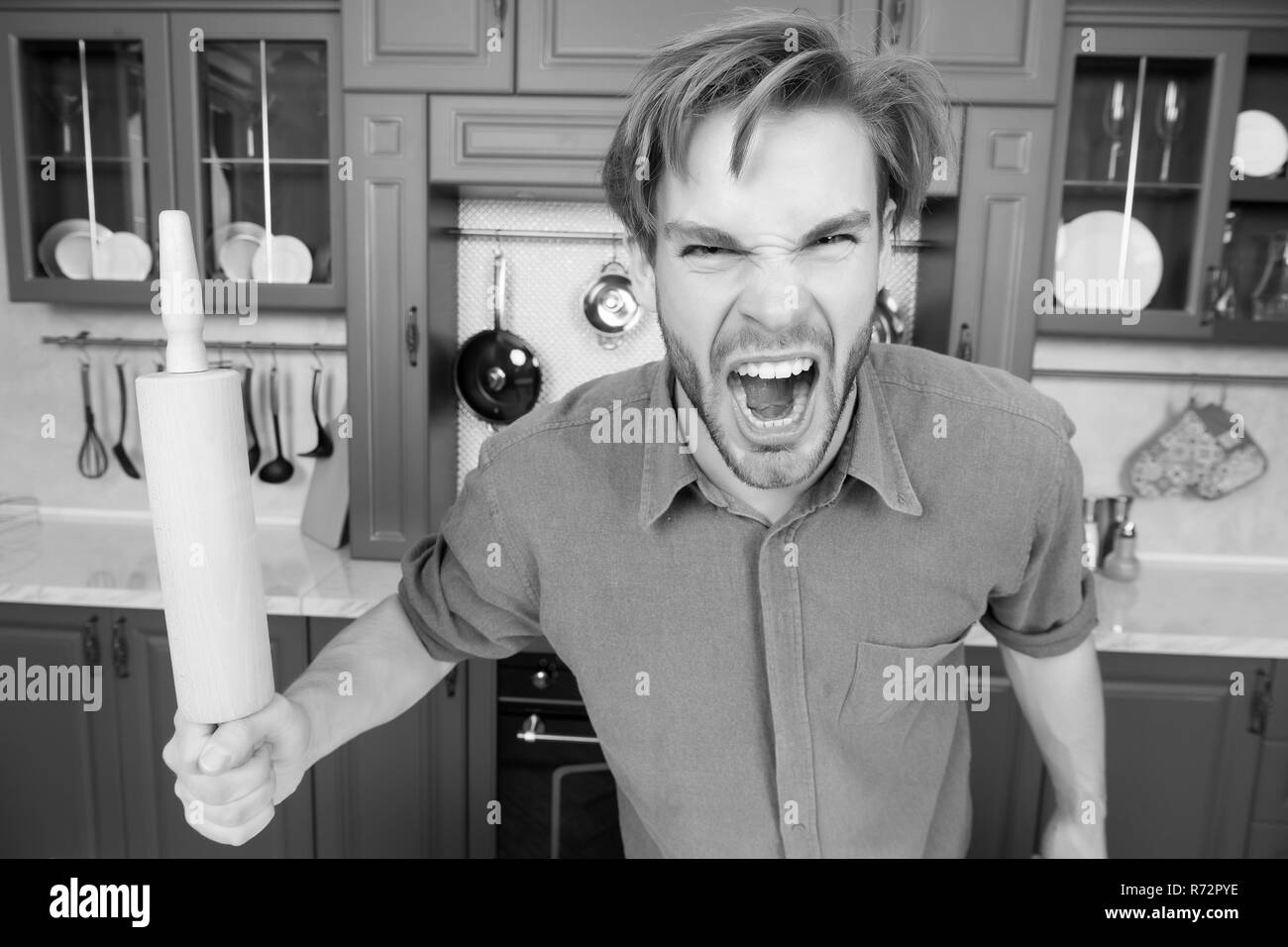 Man with angry face shout with rolling pin in kitchen. Cook, bake, home ...