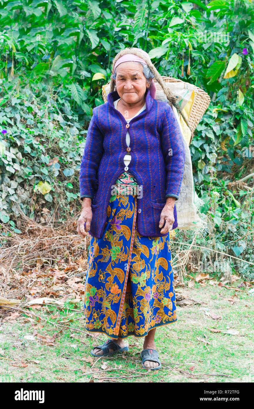 Old Nepalese woman carrying stones for road construction on her back ...