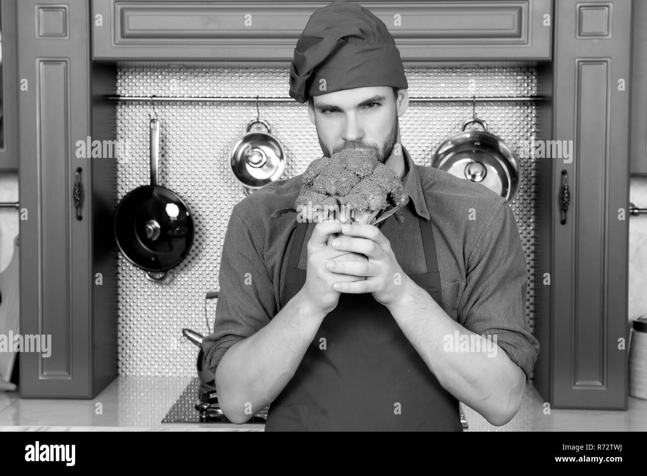 Macho in red chef hat, apron hold green broccoli vegetable in kitchen ...
