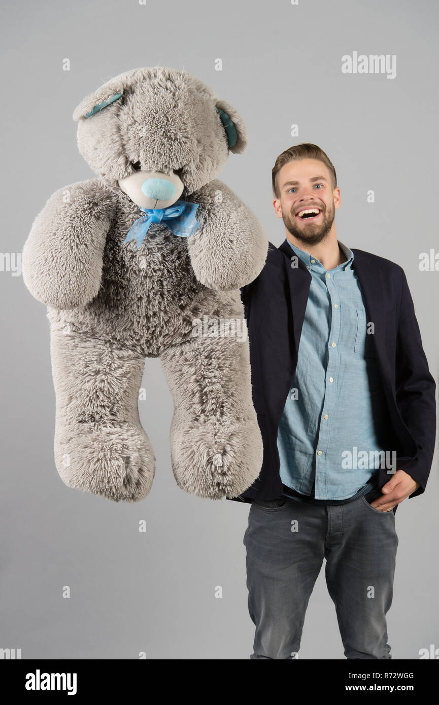 Happy man with grey teddy bear. Macho smile with big animal toy. Gift ...