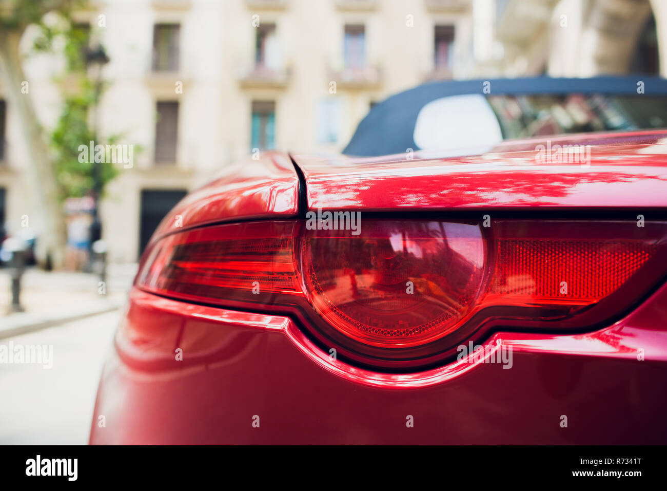 Detail of red metallized red rear car headlight in eye shape, with sun ...