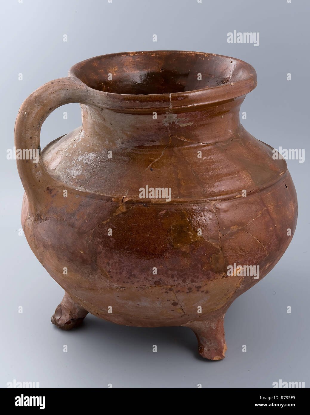 Red brown earthenware cooking jug on three legs, with sausage ear ...