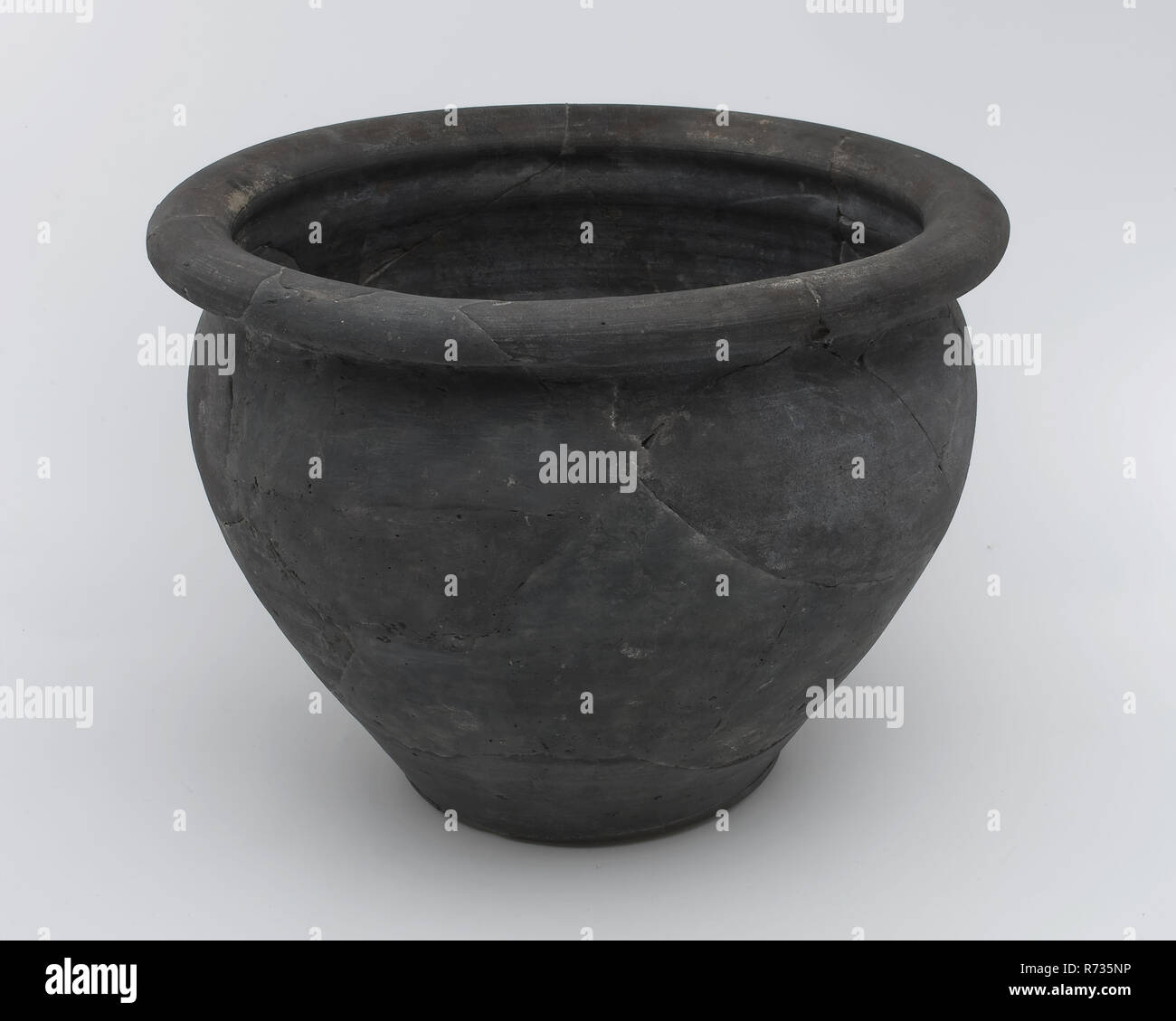 Black storage jar on standing surface, folded upper edge above ...