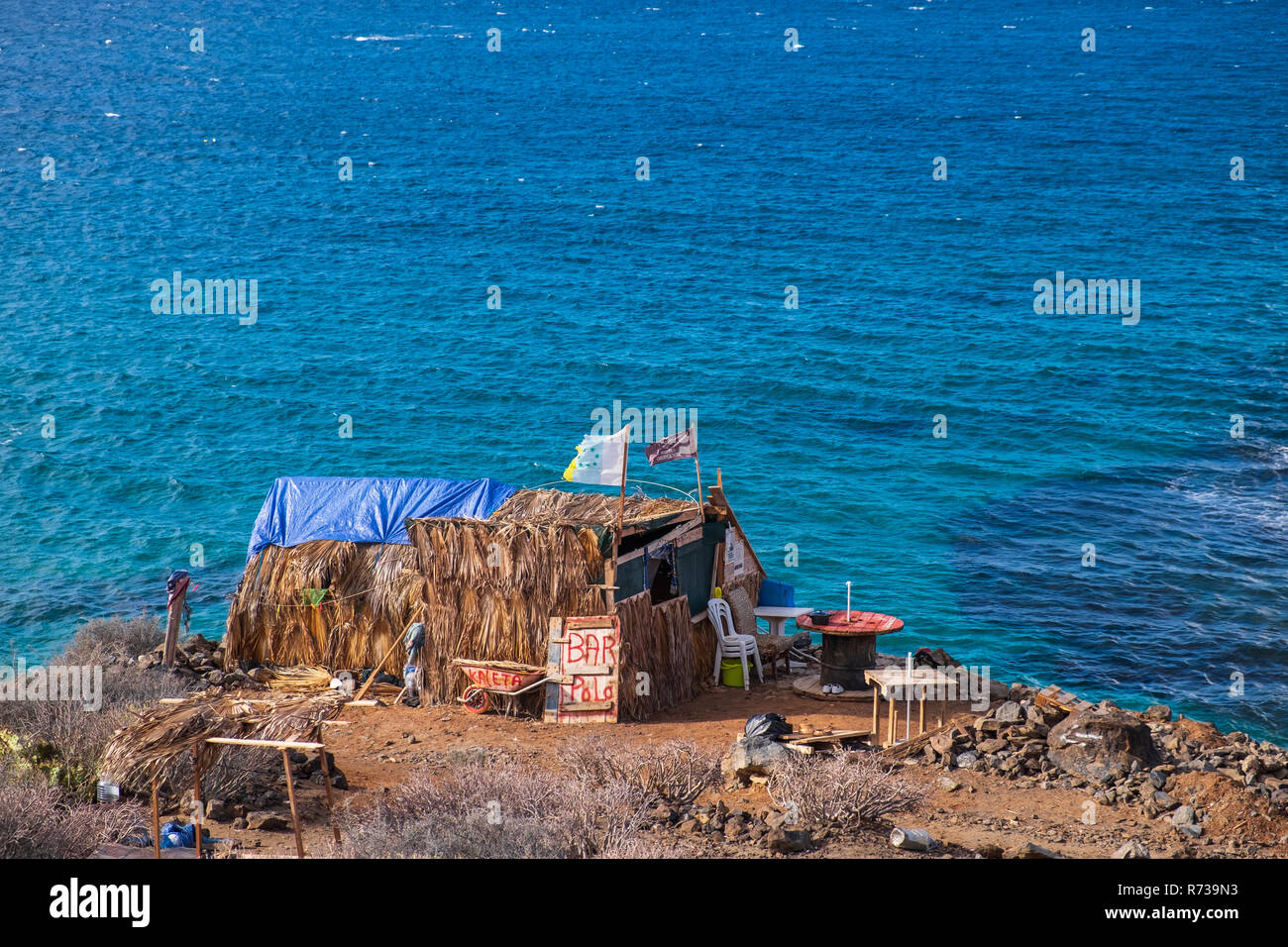 Shanty bar dwelling made from old wood, palm leaves and tarpaulin, on a ...
